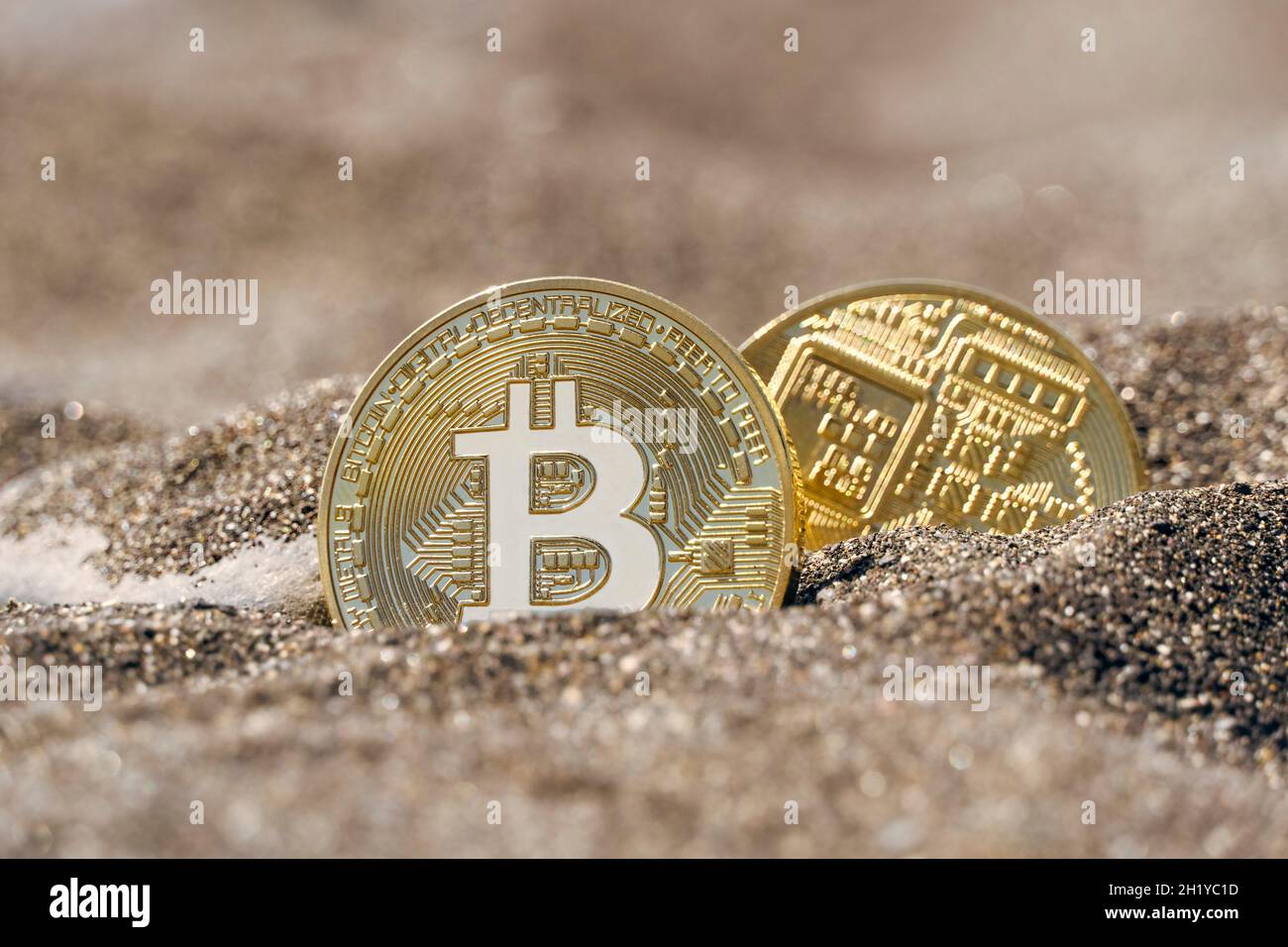 Two coins of the digital currency Bitcoin in the sand Stock Photo - Alamy