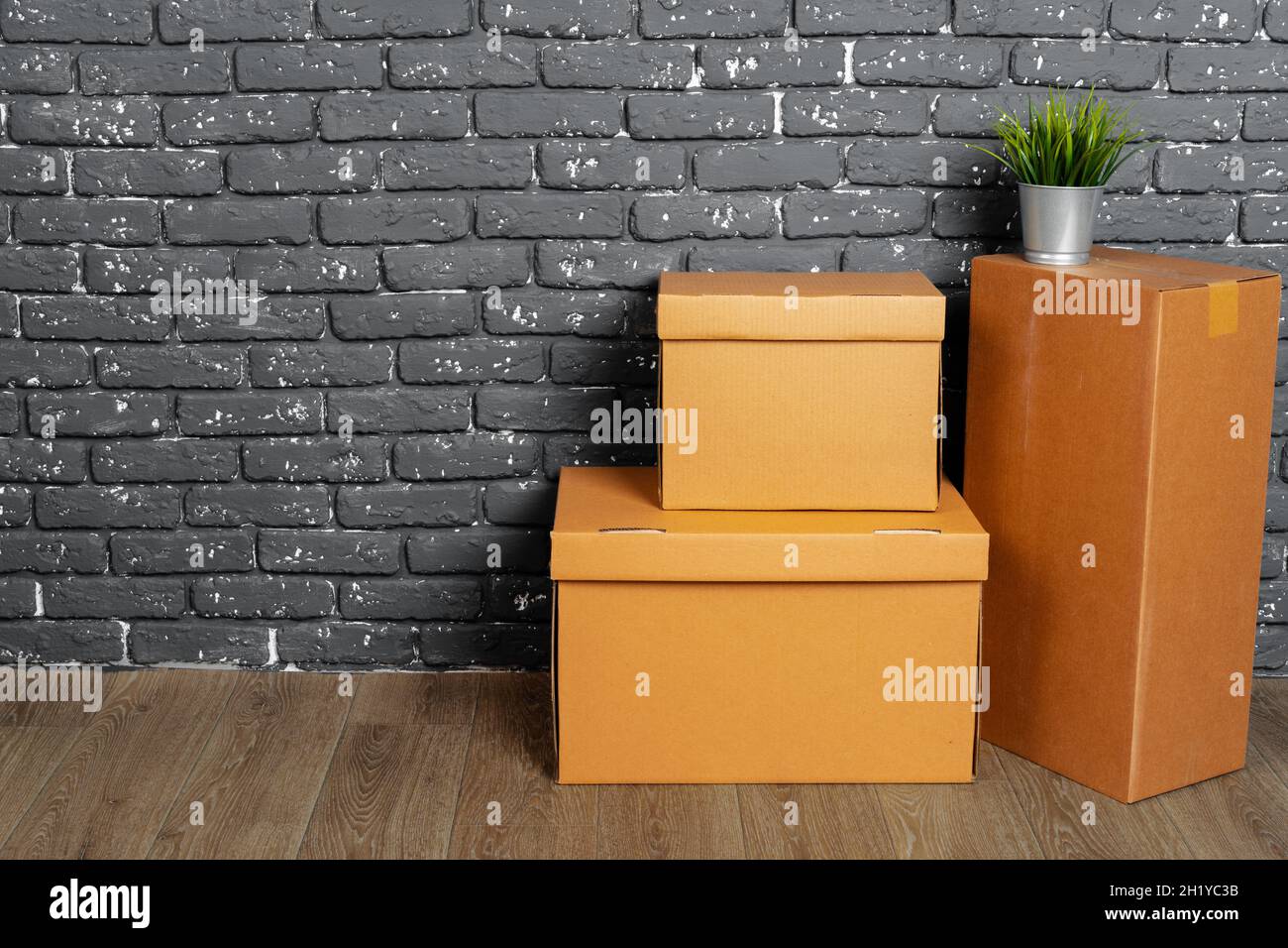 Stack of cardboard boxes in the empty room against black brick wall ...