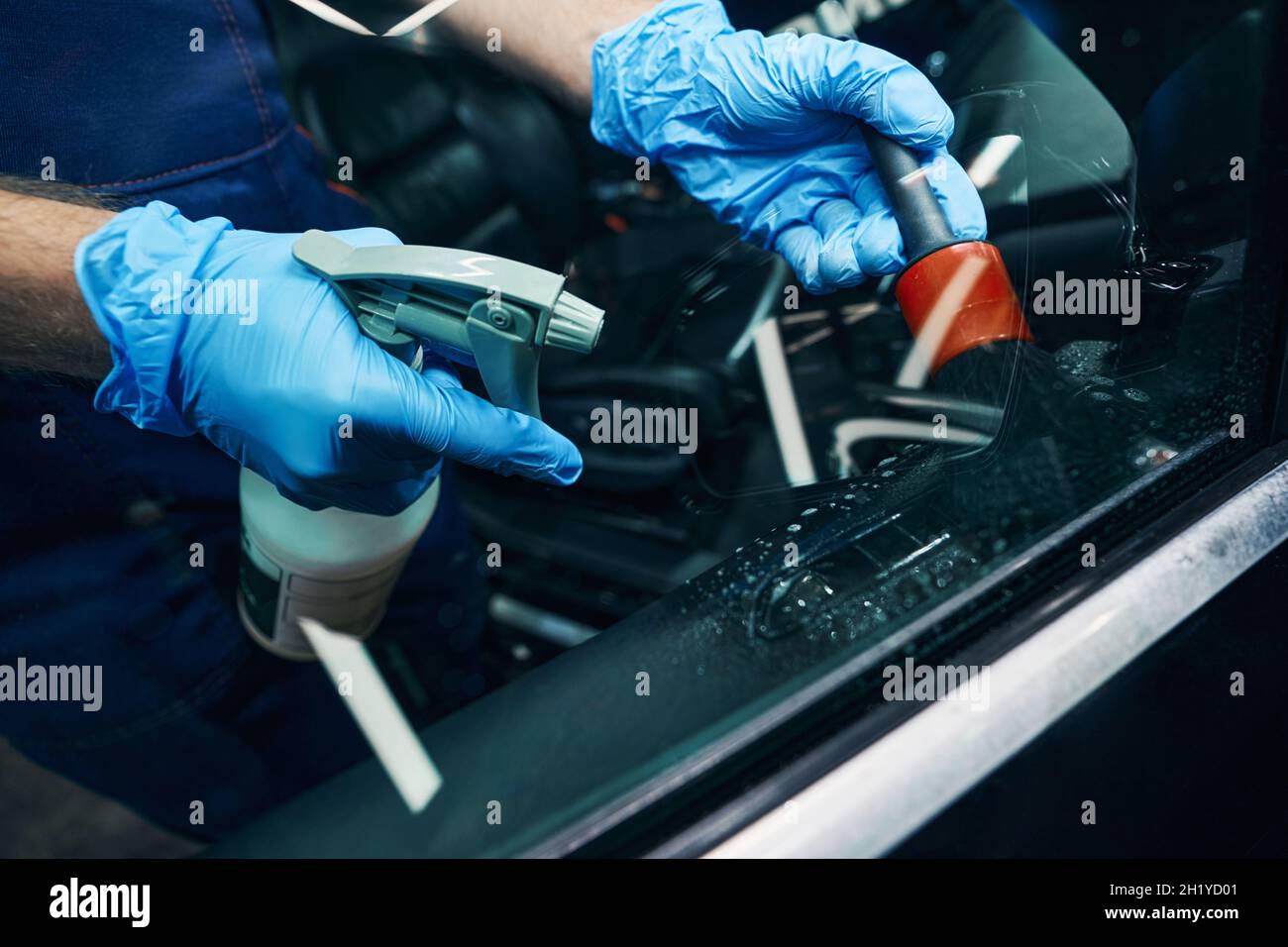 Mechanic is spraying window with cleaning detergent Stock Photo - Alamy