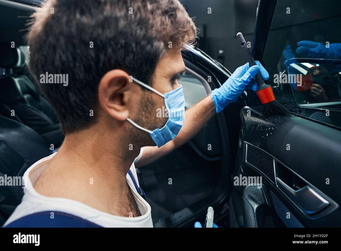 Worker cleaning panel under car window with brush Stock Photo - Alamy