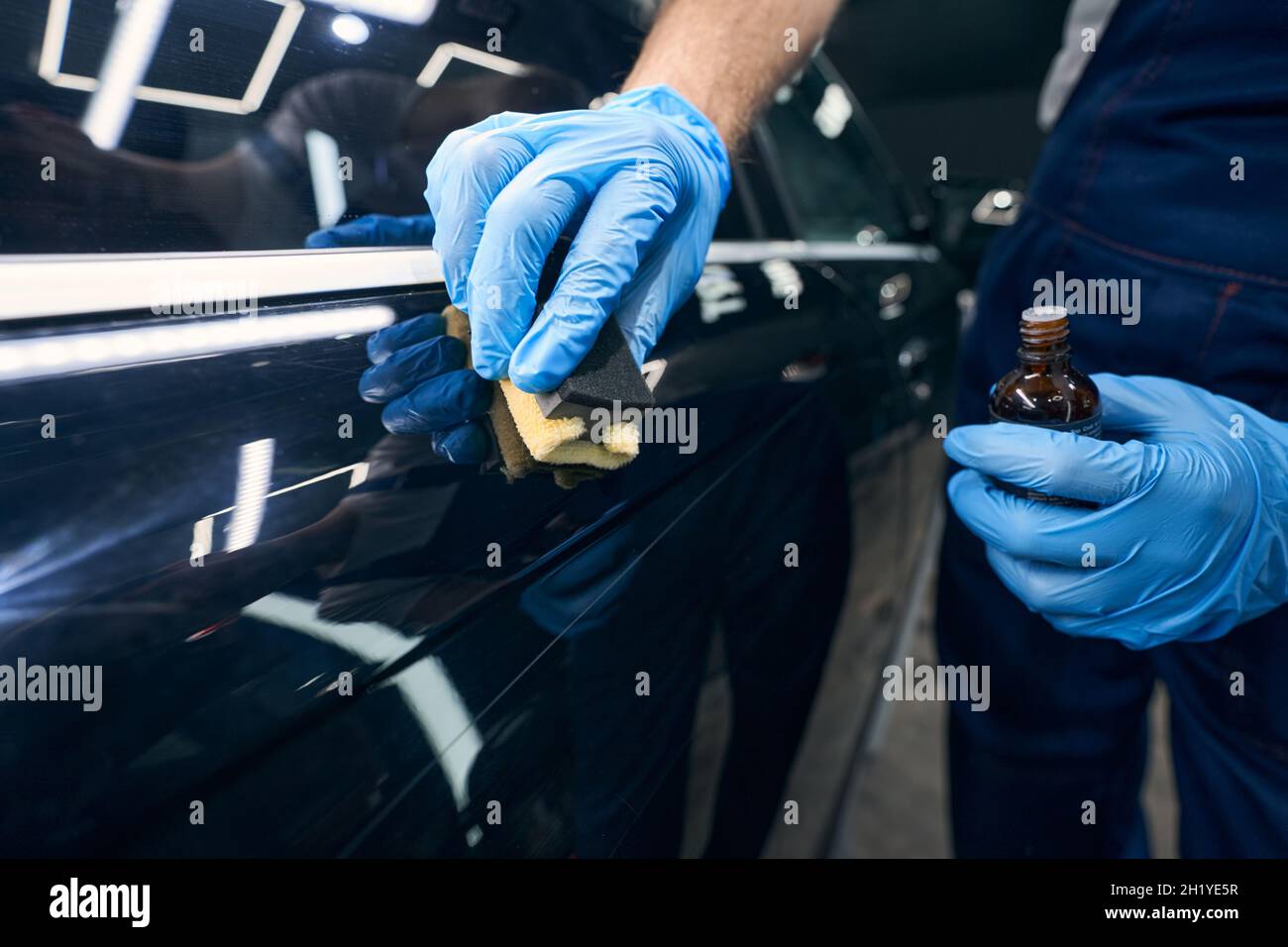 Worker with microfiber applicator spreading ceramic coating on car ...
