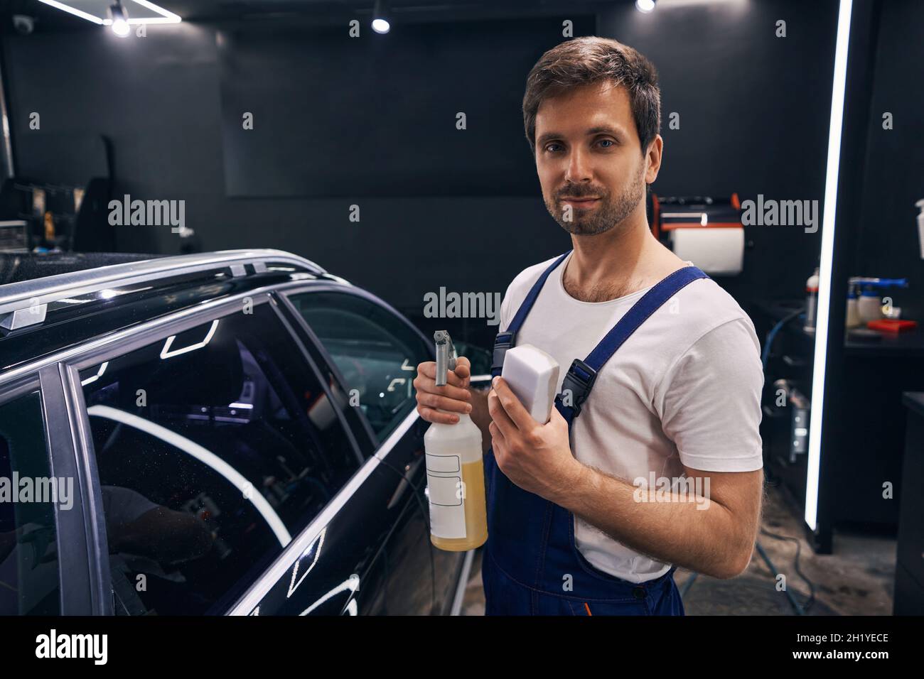 Worker of repair shop posing with cleaning liquid and sponge Stock ...