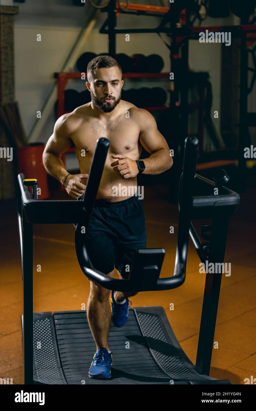Full-length portrait of young sportive man running on a treadmill ...