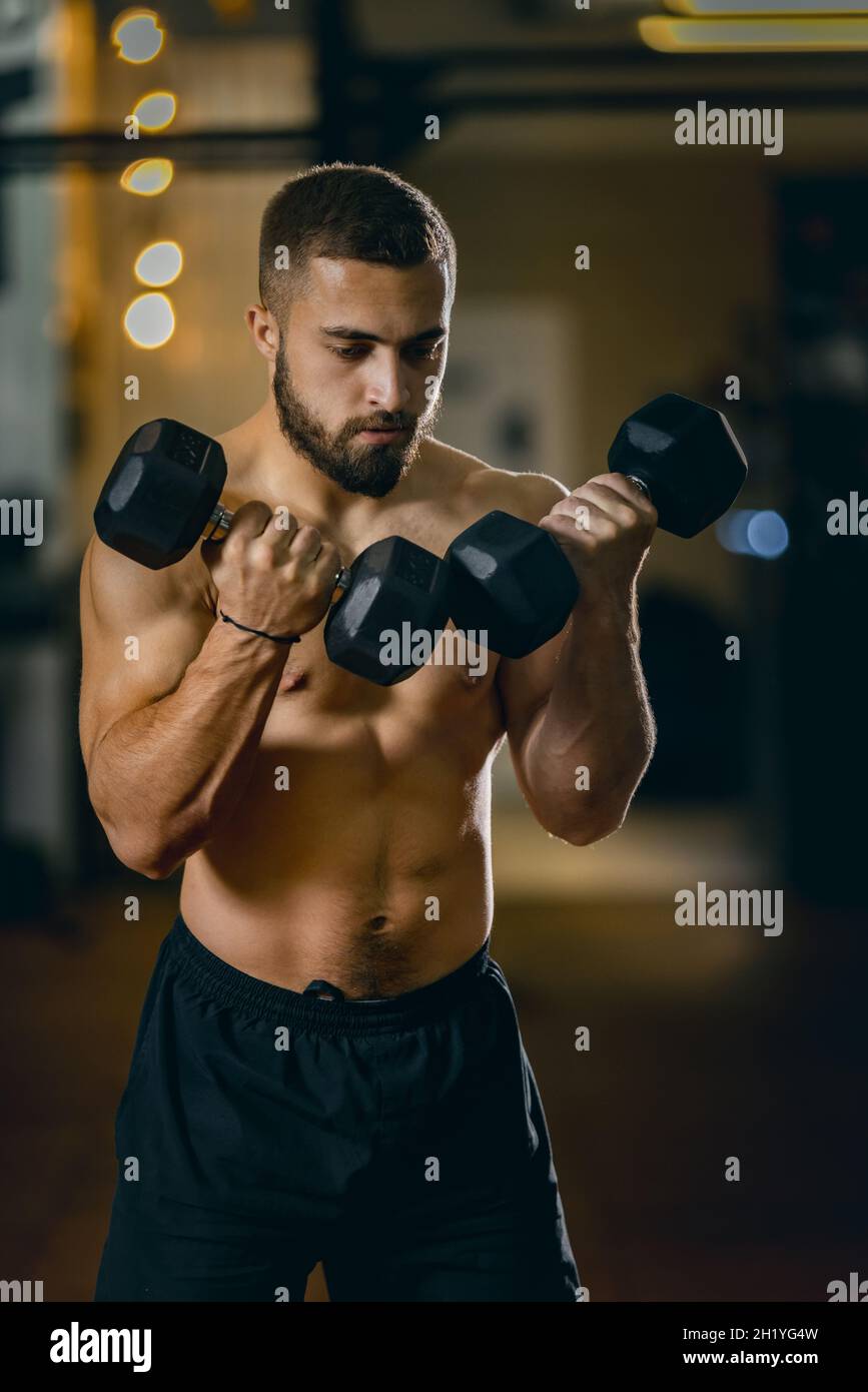 Full-length portrait of young sportive man training, pumping hands with ...