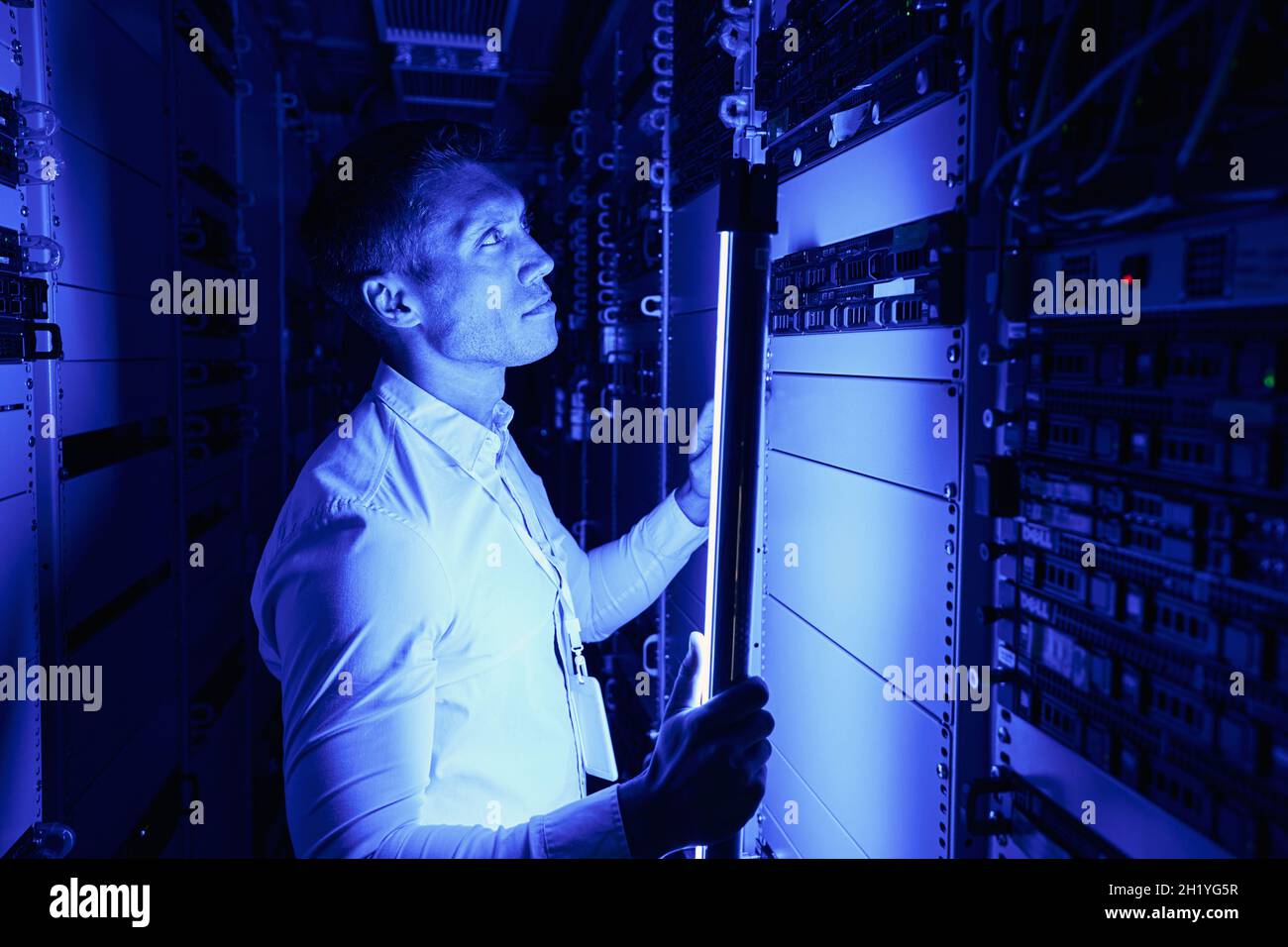 Employee using additional lighting for checking hardware equipment ...