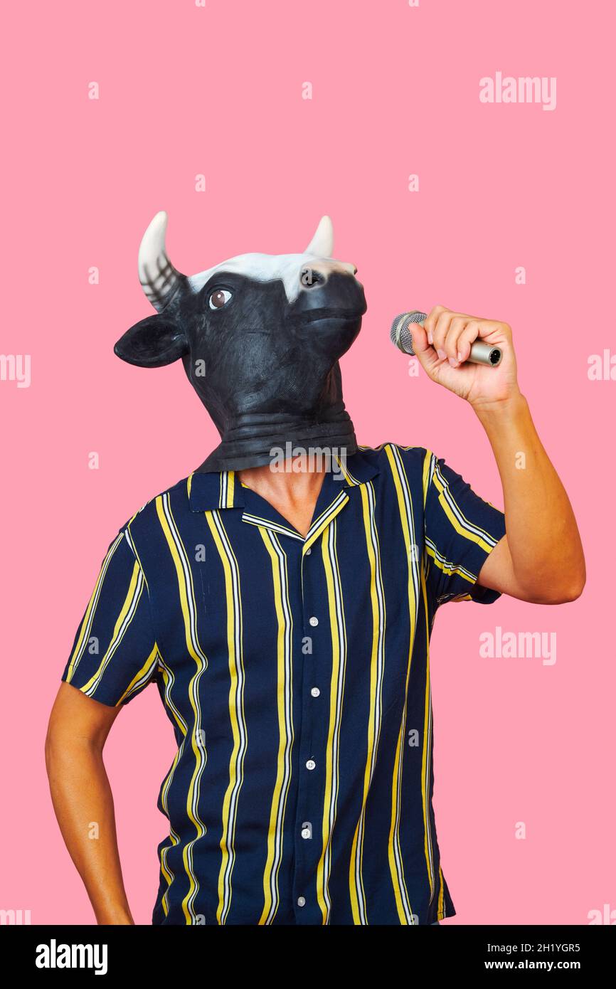 closeup of a young man wearing a cow mask speaking into a microphone ...