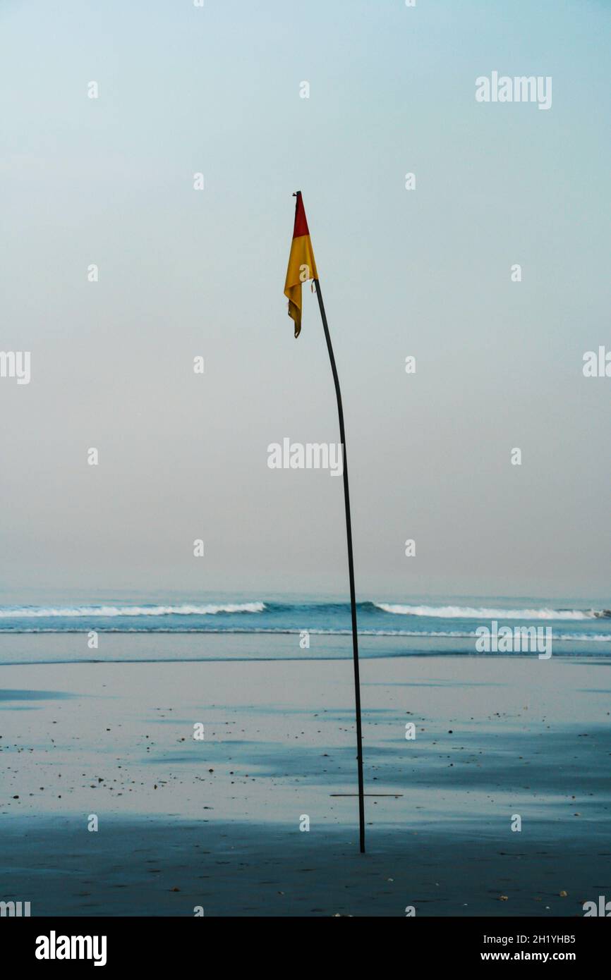 Warning flag for safety in beach during sunrise with water reflection ...