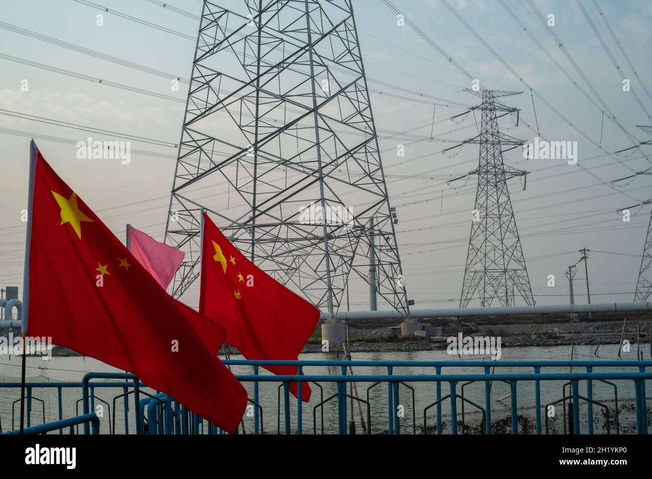 Chinese flag waving in front of high-voltage transmission towers in ...