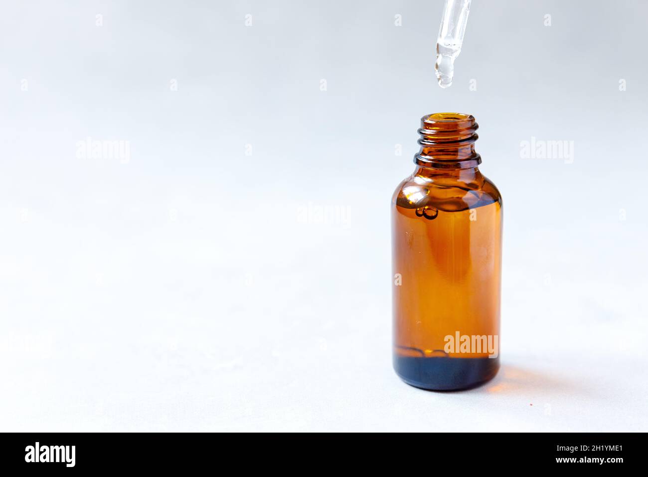 Essential oil dropping from pipette to bottle. Essence liquid cosmetic ...