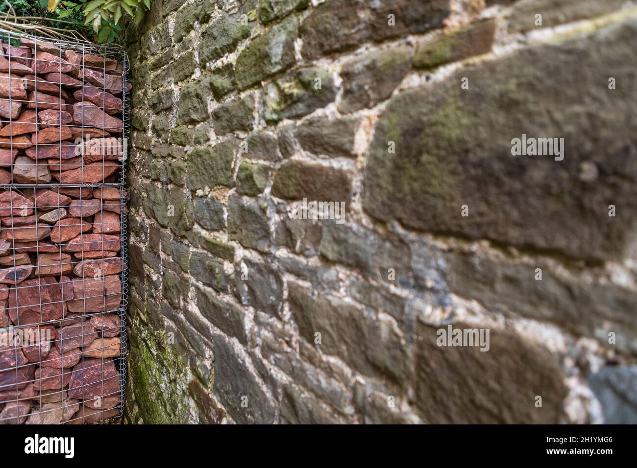 Old stone masonry with lime mortar wall and a new style steel cage ...