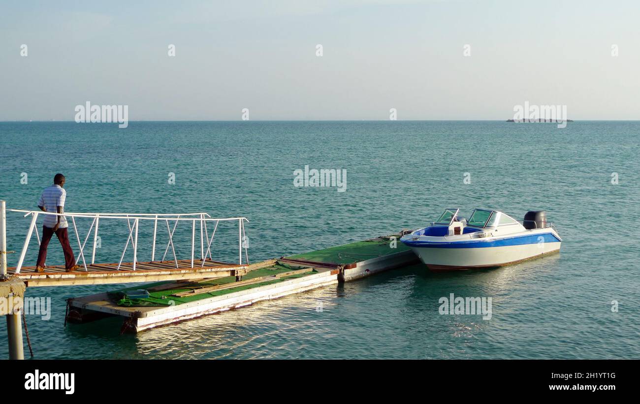 African black man walking on the pier towards a speedboat floating in ...