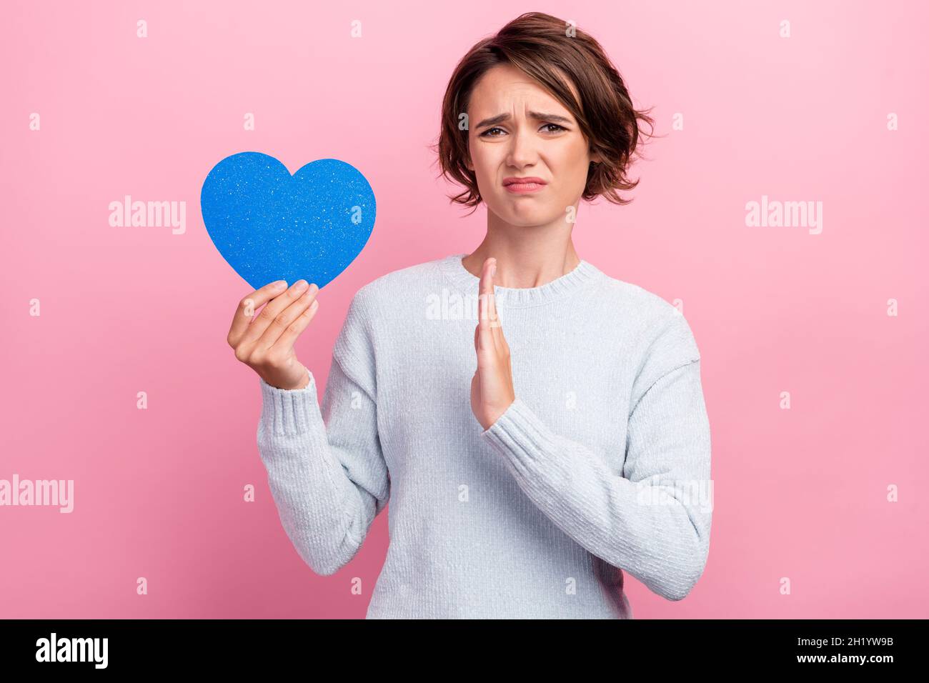 Photo of unhappy upset sad young woman hold blue heart paper shape hand ...