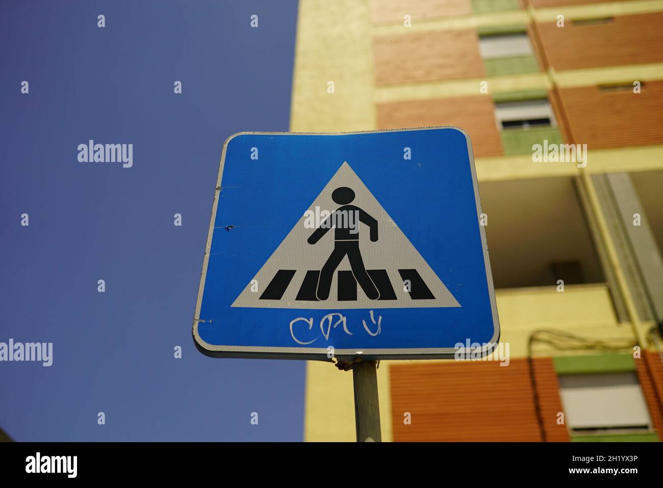 Low angle of the blue metal crosswalk sign against the blue sky on the ...