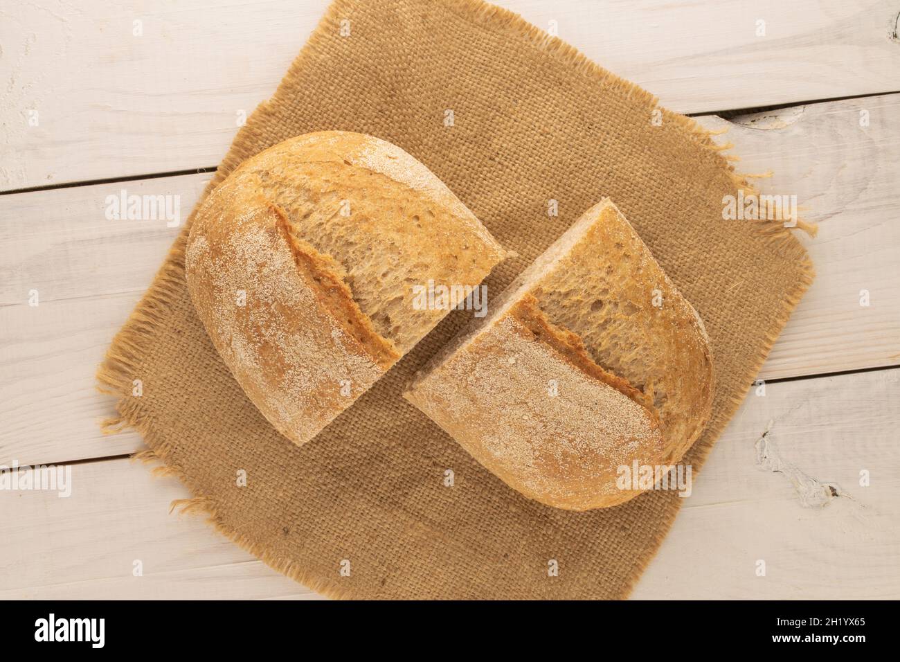 Two half fragrant loaf without yeast with bran flakes on jute fabric ...
