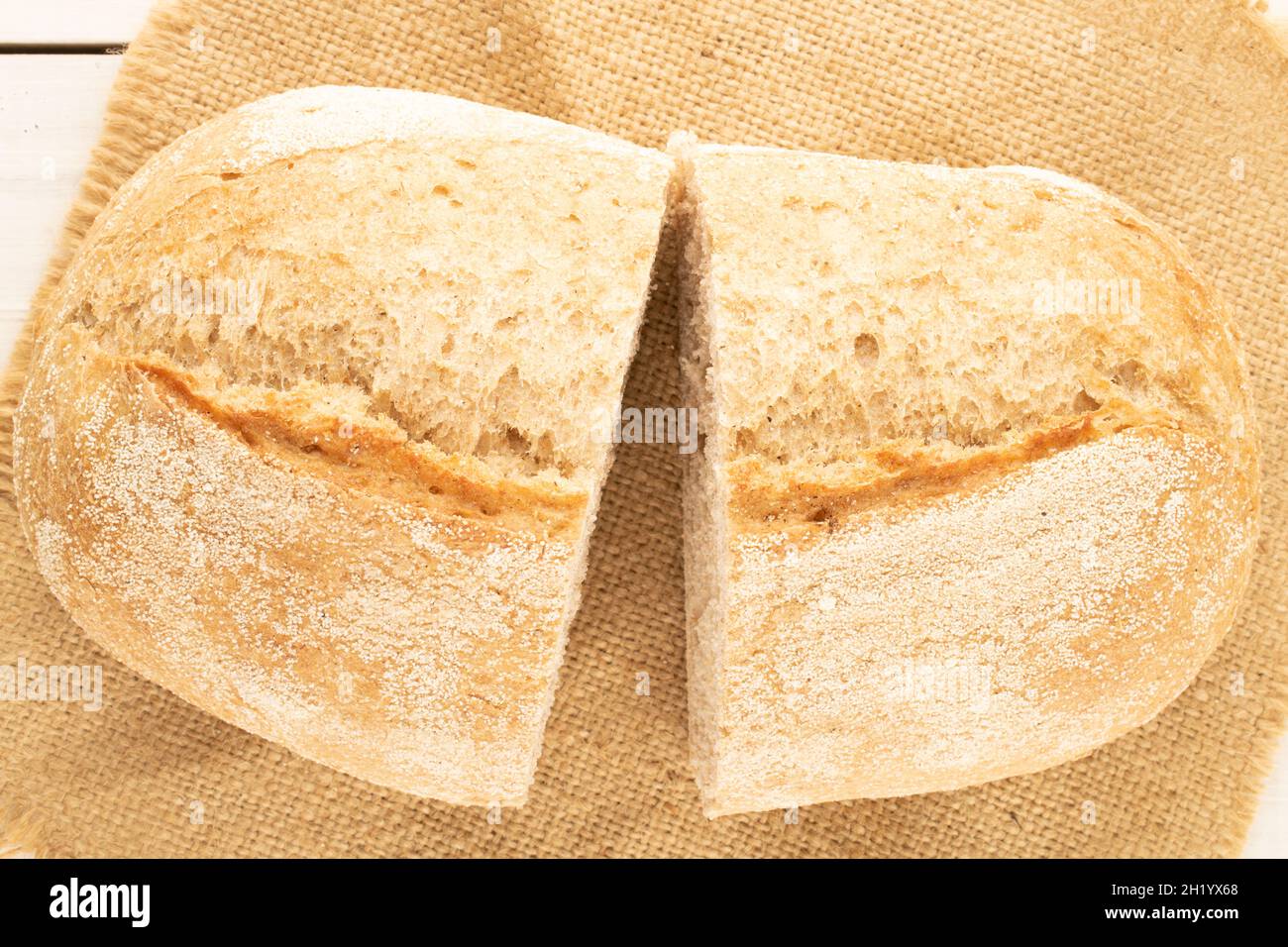 Two half fragrant loaf without yeast with bran flakes on jute fabric ...