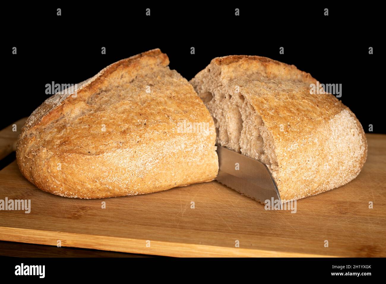 Two halves of a fragrant loaf without yeast with bran flakes on a ...