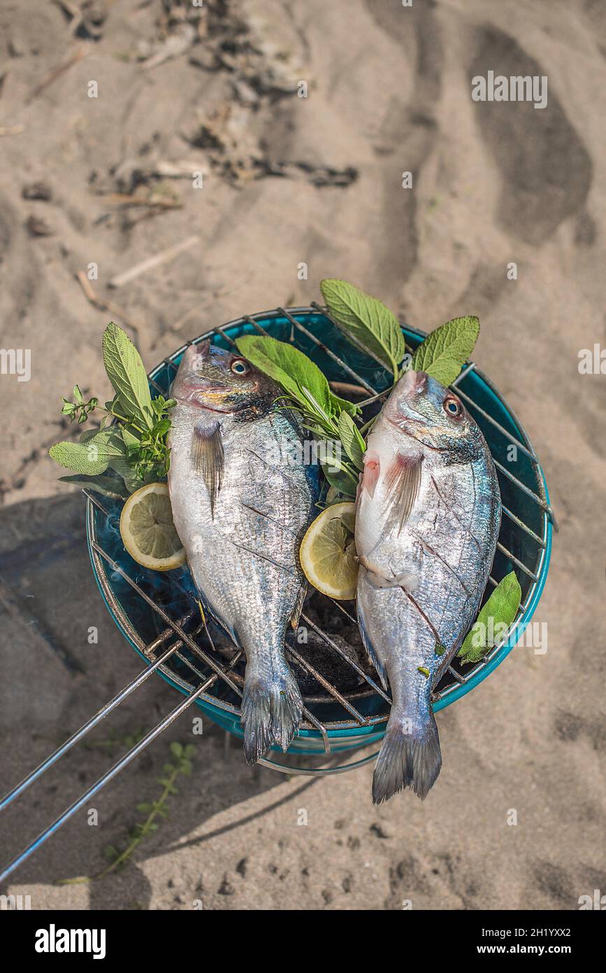 Fish barbecued on a beach with herbs and lemon Stock Photo - Alamy