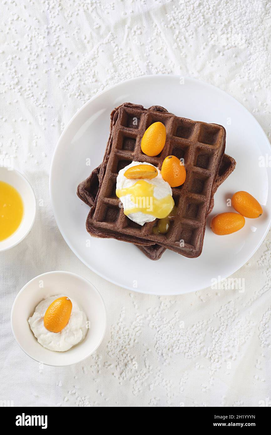 Cocoa waffles with orange sauce, ricotta and kumquats Stock Photo - Alamy