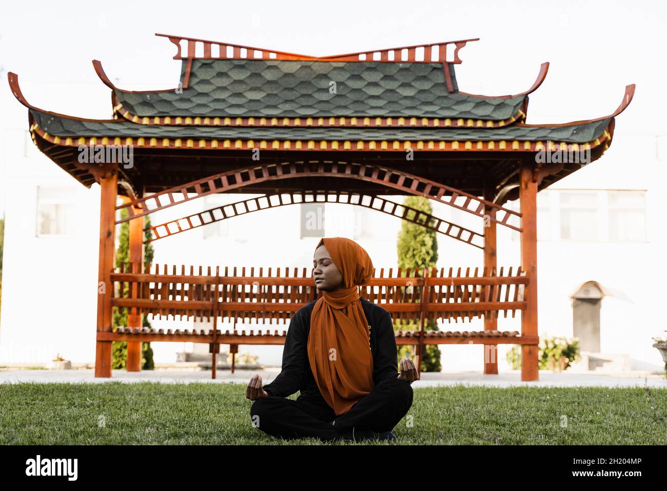 Black muslim woman meditating yoga near chinese arbor. African girl is ...