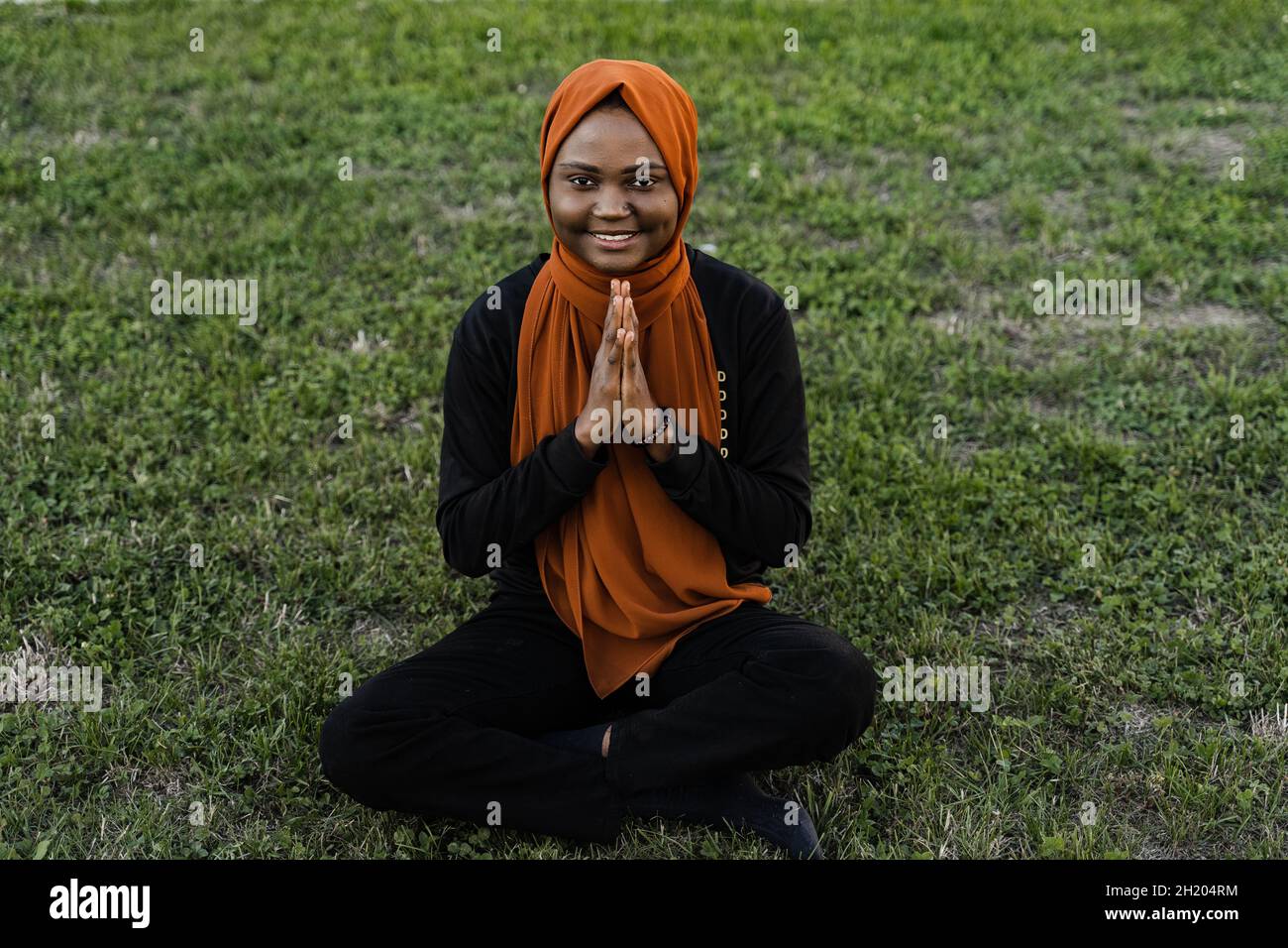 Black muslim woman meditating yoga and pray on grass. Lifestyle of ...