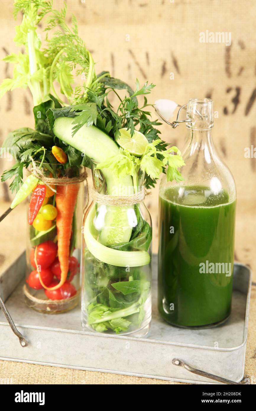 Healthy mixed vegetable juice with ingredients in glasses and a bottle ...