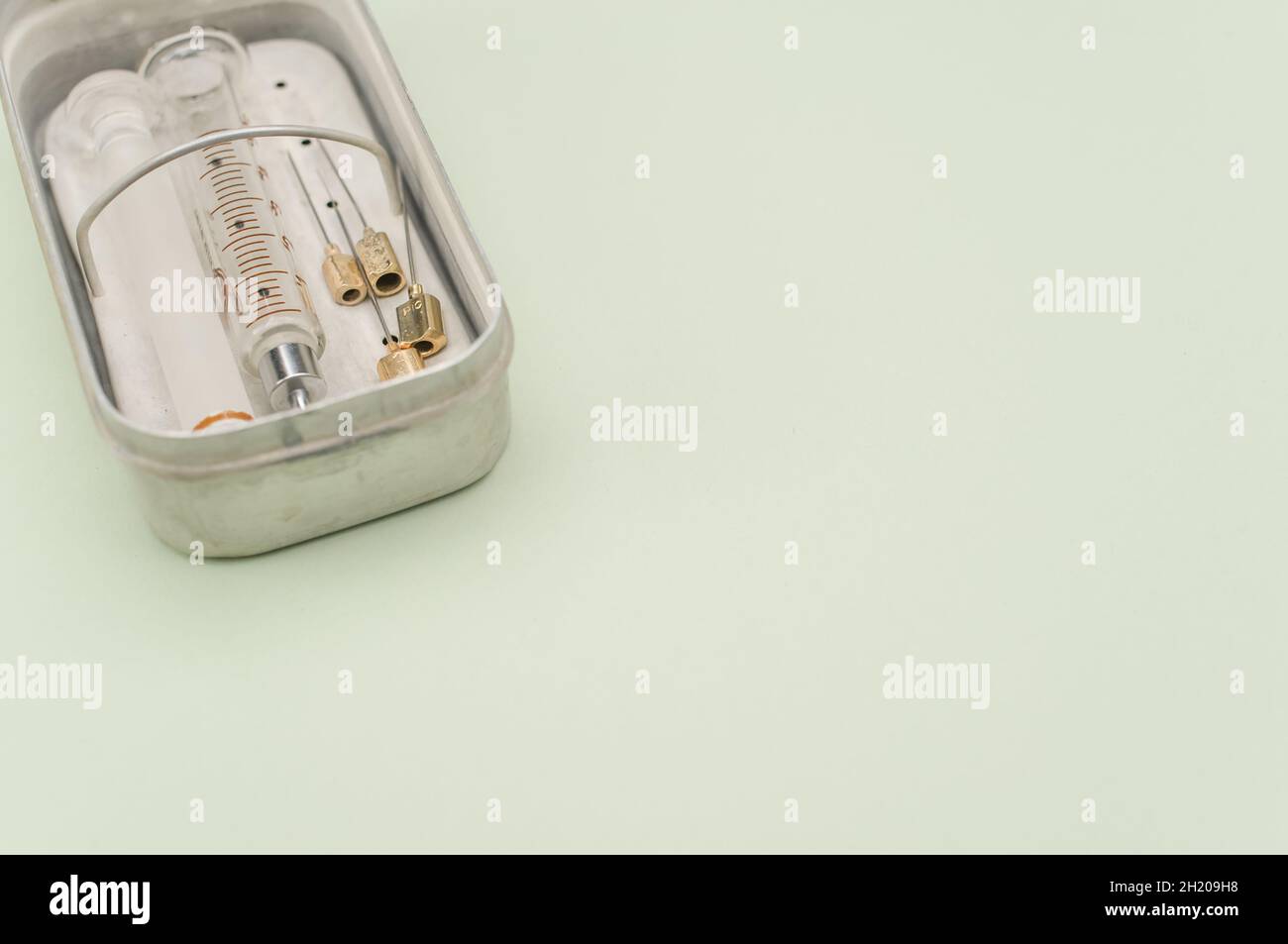 isolated sterilized glass injection syringe in a box on a green ...