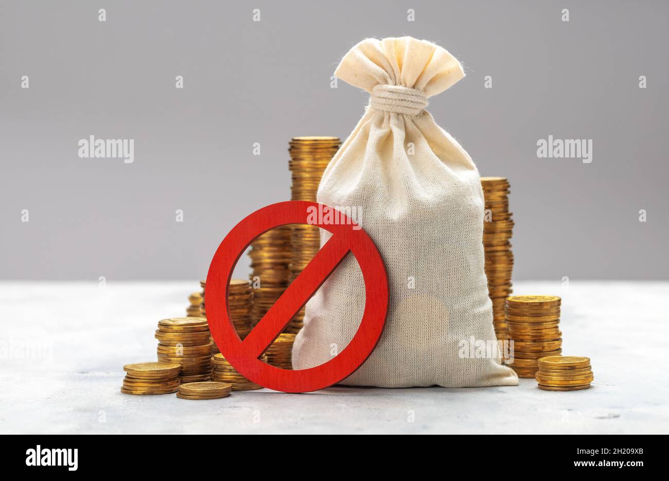 Prohibition sign. Money bag and stacks of coins on a gray background ...