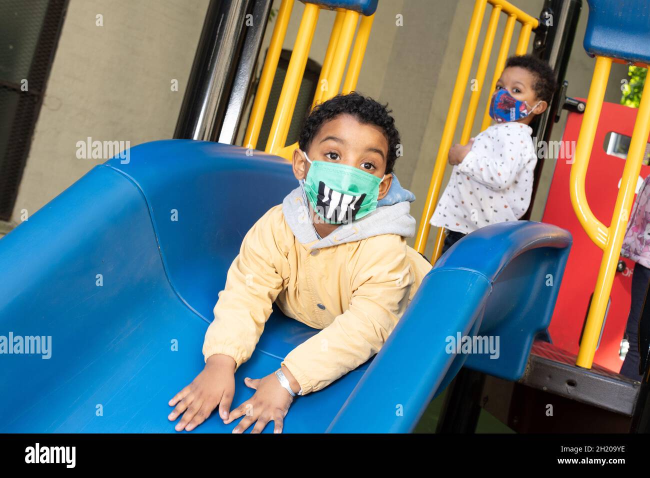 Education Preschool playground boy playing on slide wearing face mask ...