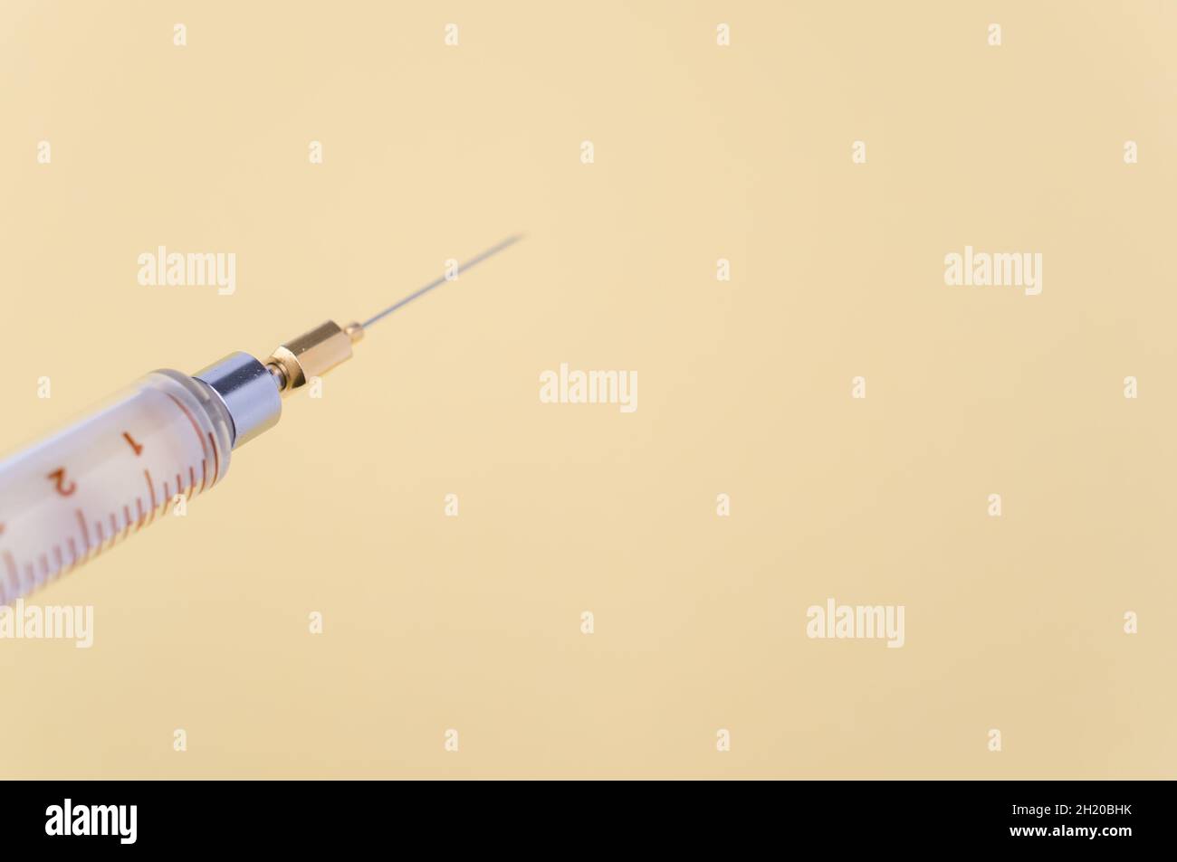 isolated sterilized glass injection syringe on a yellow paper ...