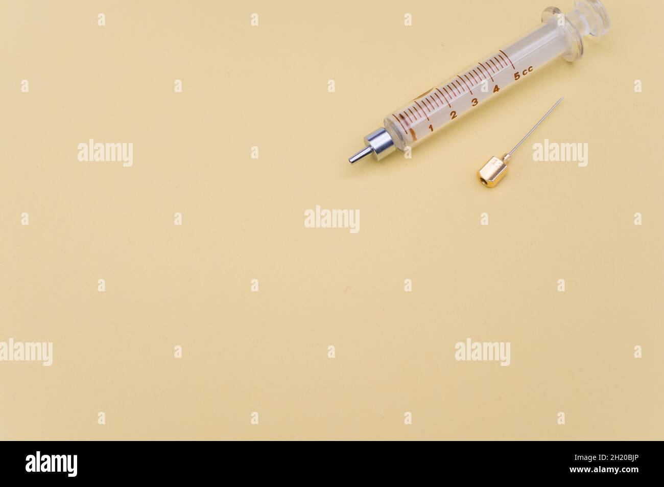 isolated sterilized glass injection syringe on a yellow paper ...