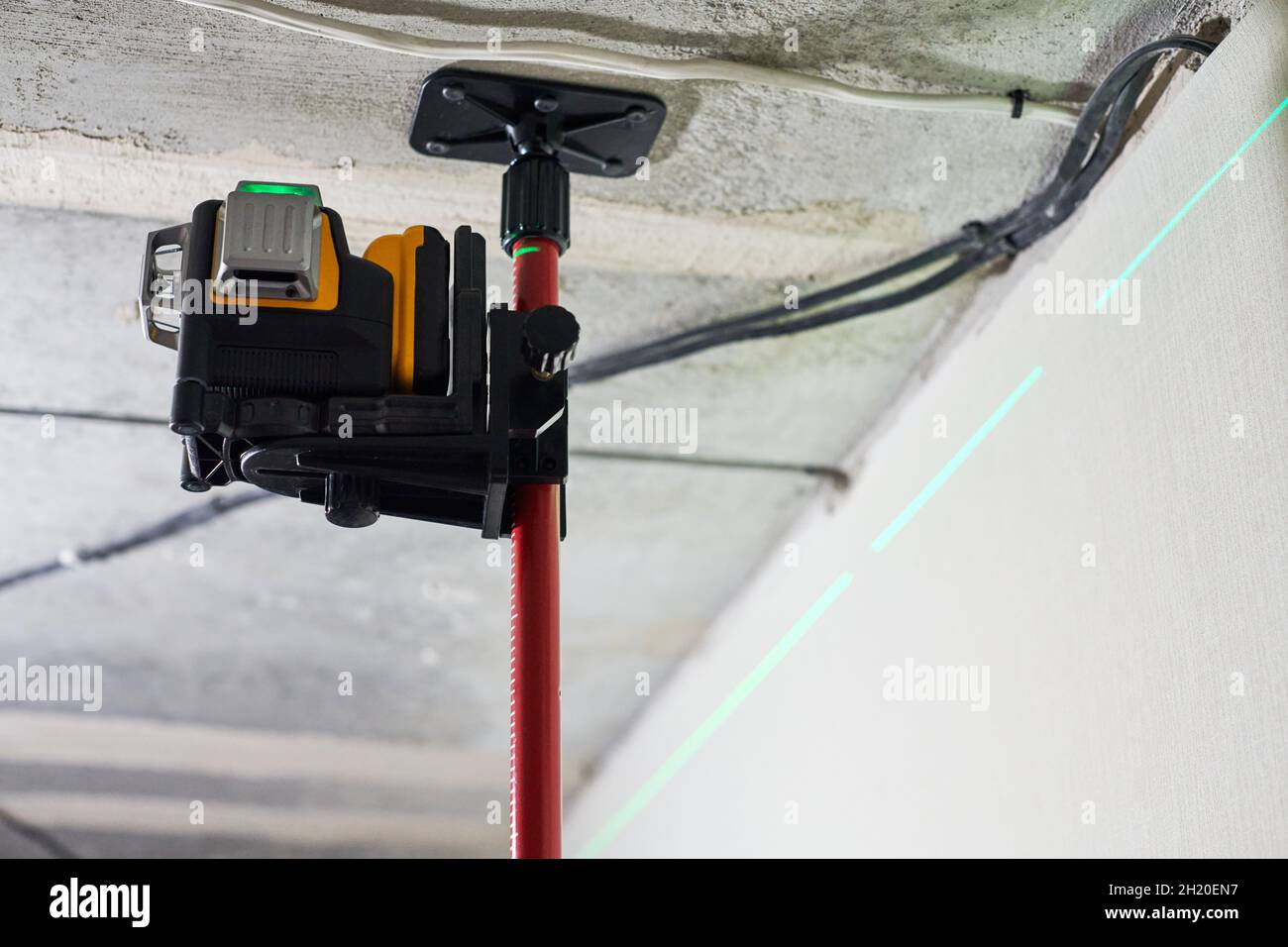 Laser level measuring tool with visible green laser beam on wall at ...