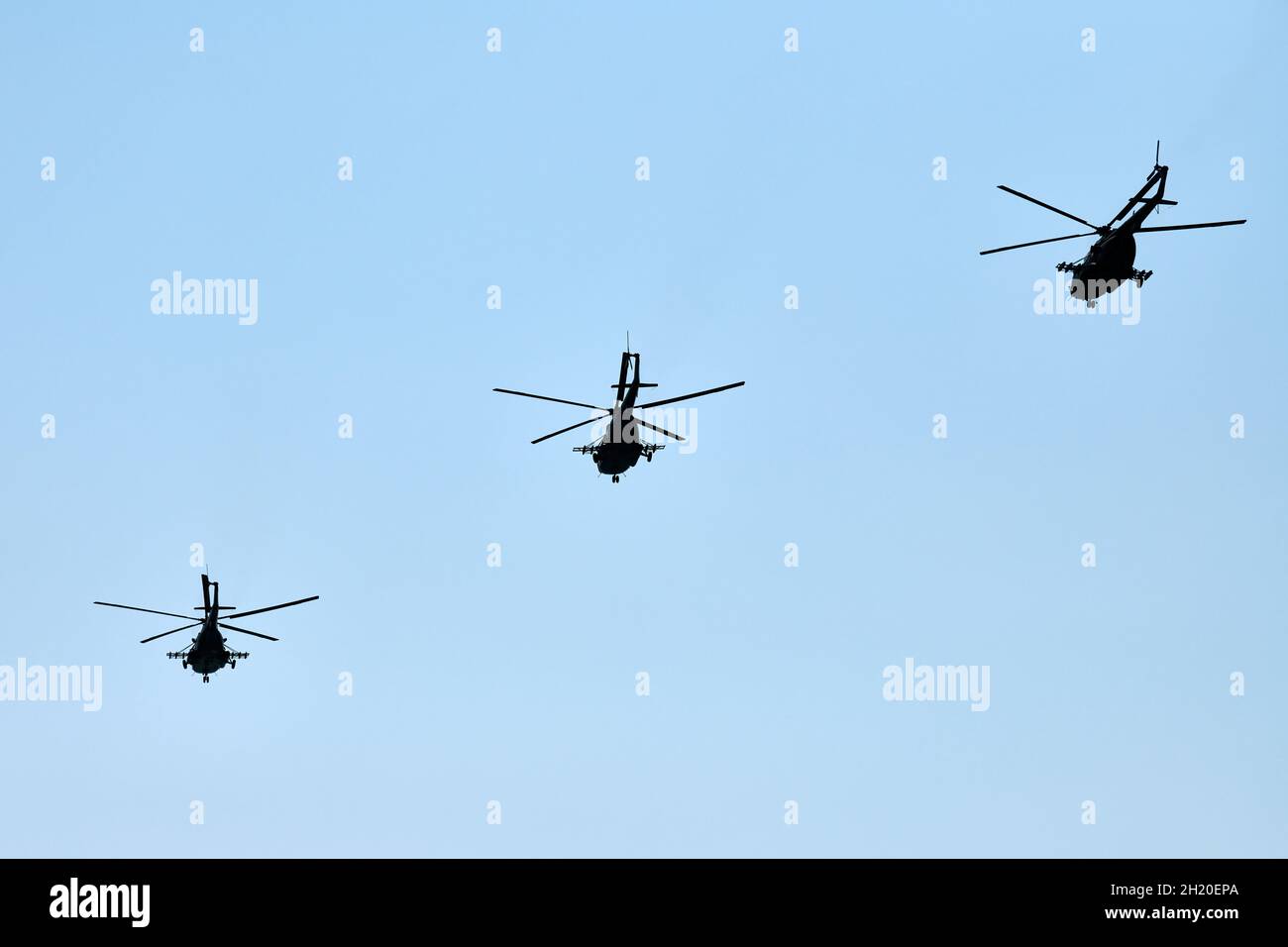 Military helicopters flying in bright blue sky performing demonstration ...