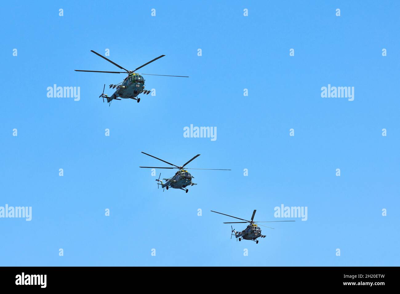 Three military helicopters flying in bright blue sky while performing ...