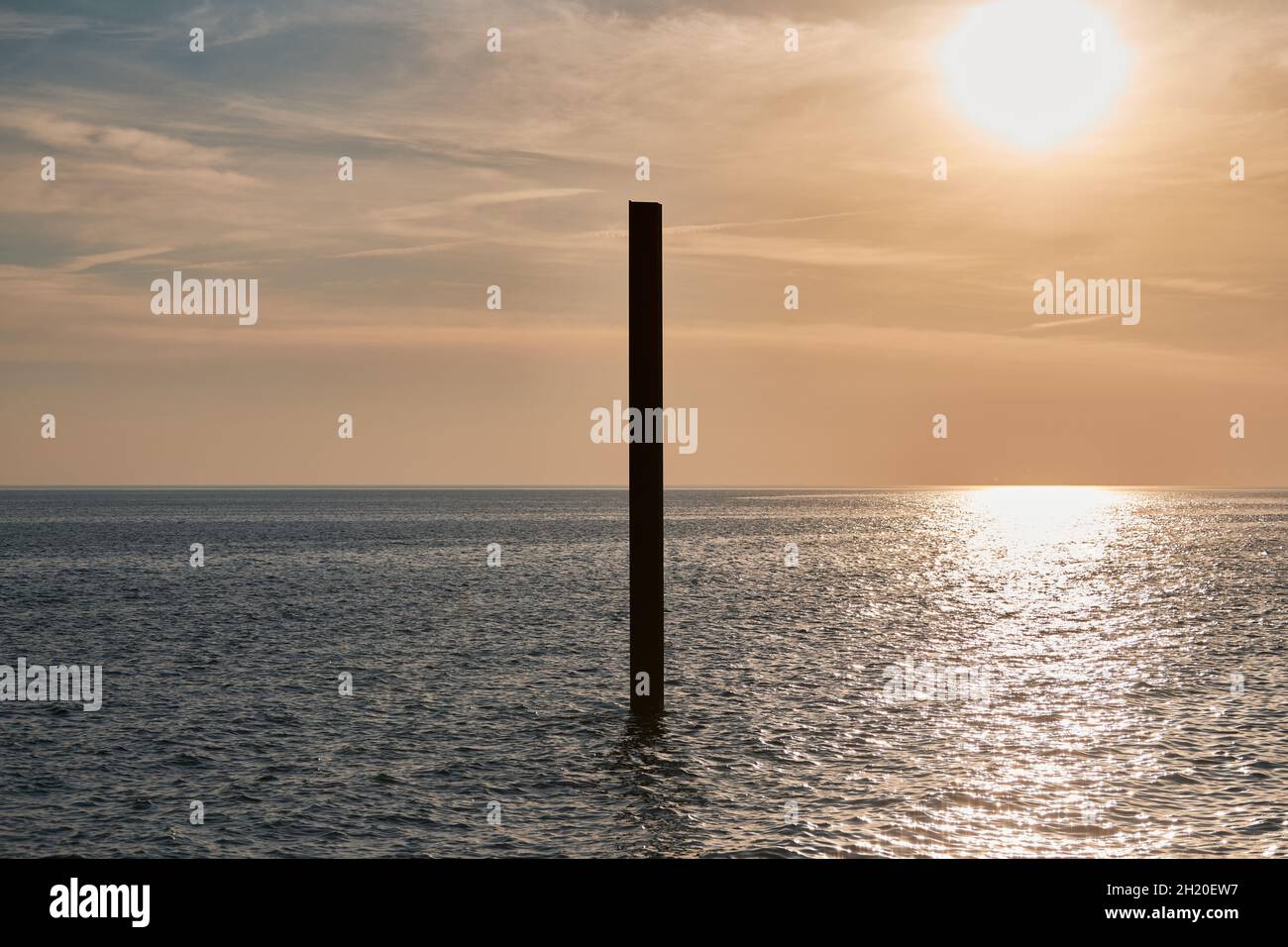 Large rusty steel construction pillar in blue sea with calm waves at ...