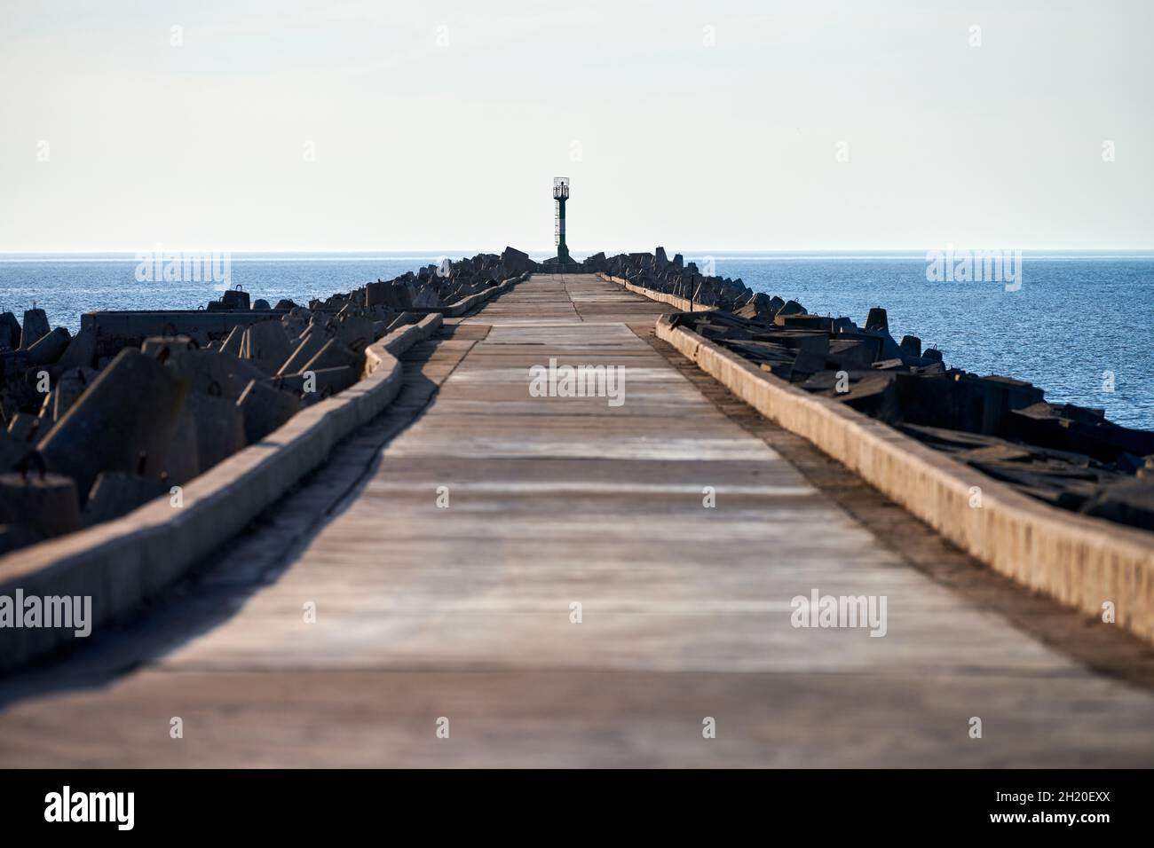 Empty long reinforced concrete pier with signal lighthouse in port ...