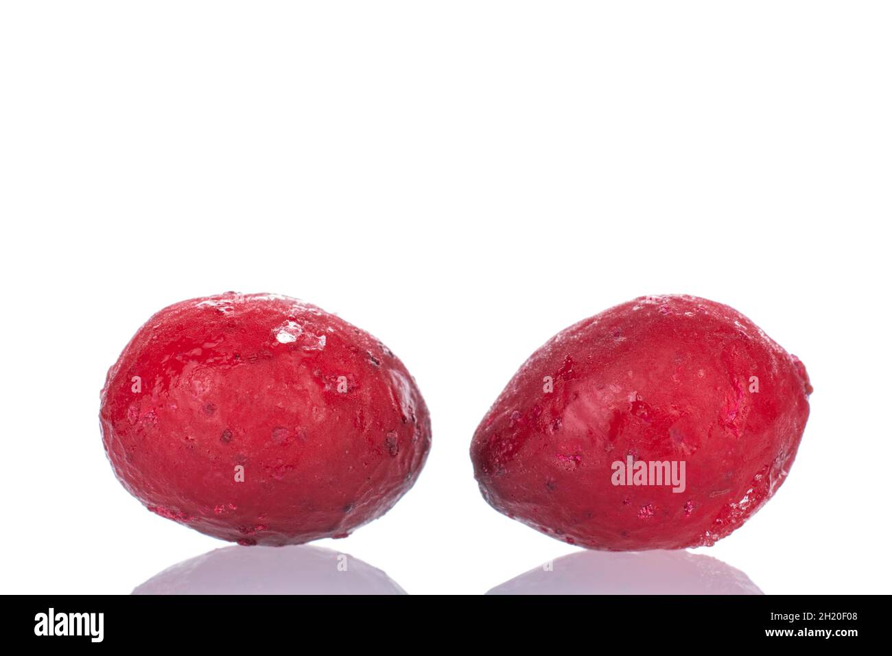 Two berries of red freshly frozen cranberries, close-up, isolated on ...