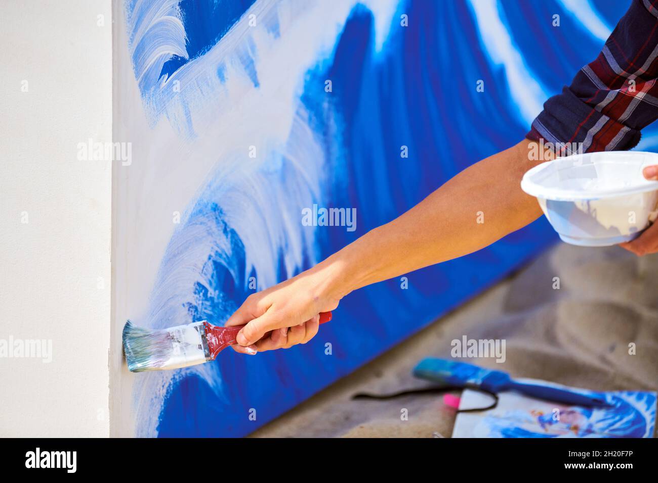 Female artist working on abstract acrylic painting, hand moving paint ...