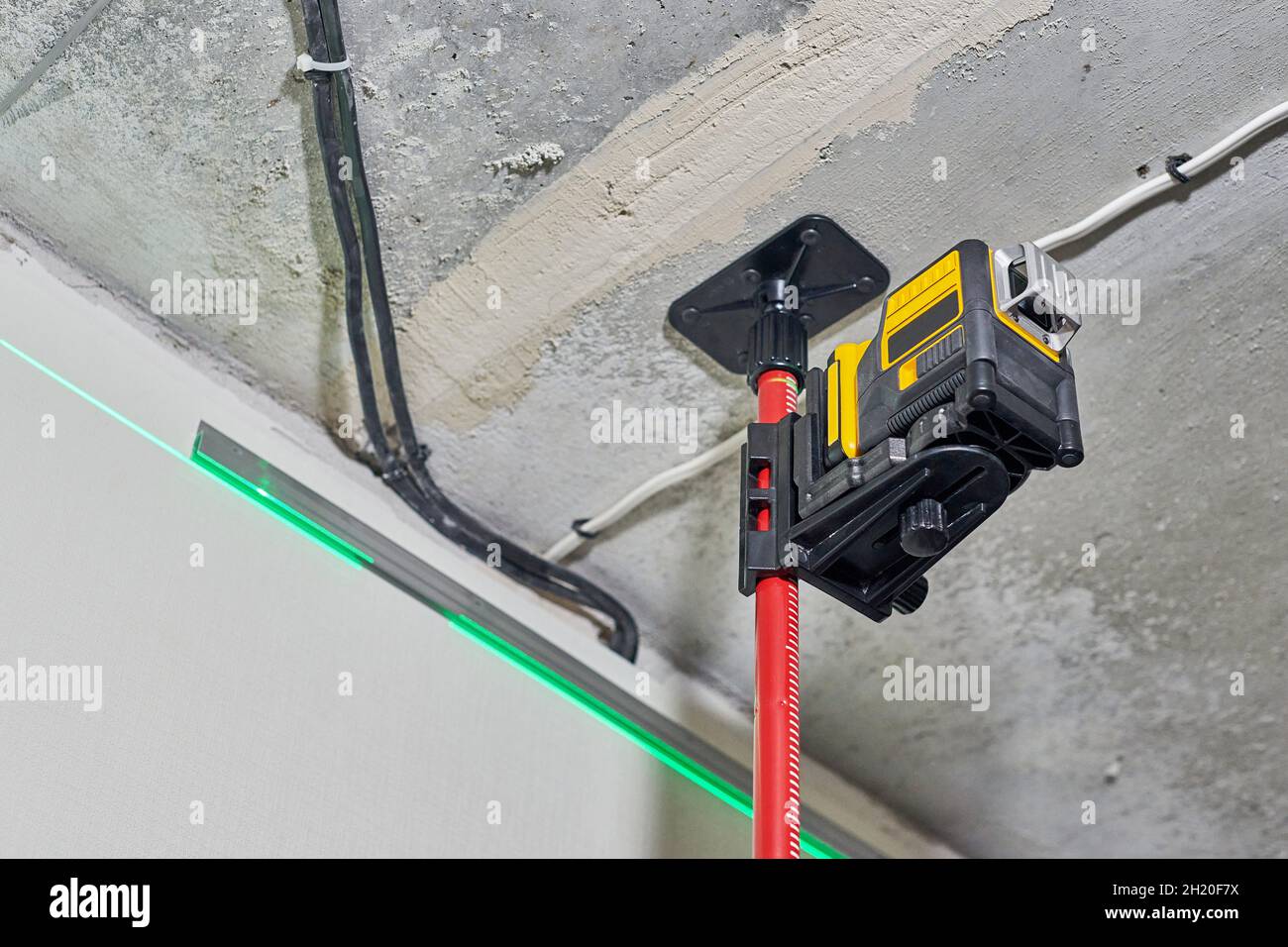 Laser level measuring tool with visible green laser beam on wall at ...