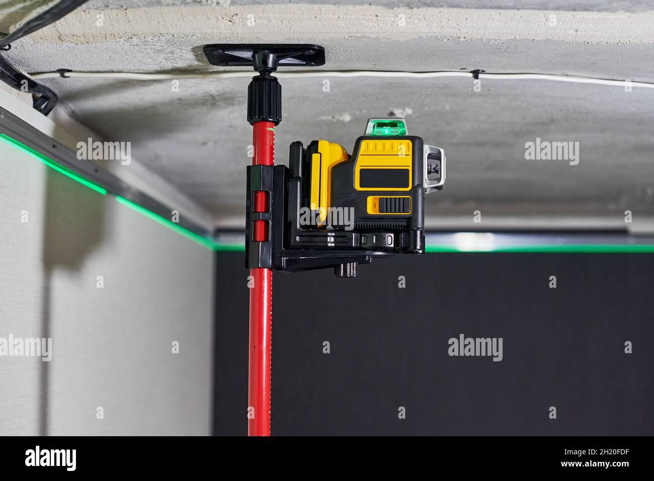 Laser level measuring tool with visible green laser beam on wall at ...