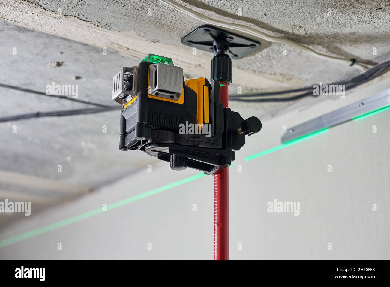 Laser level measuring tool with visible green laser beam on wall at ...