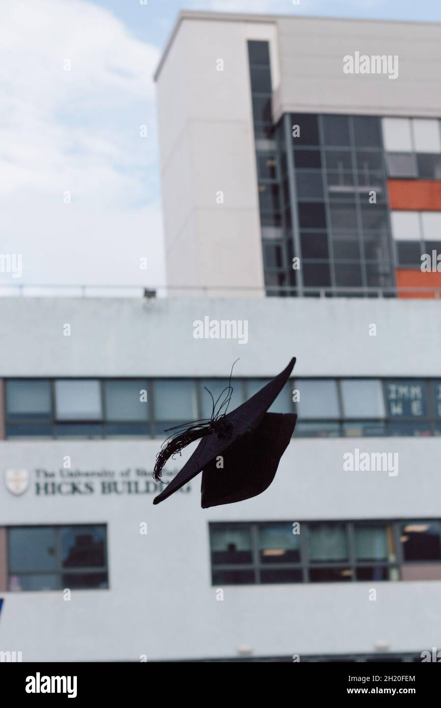 Graduate throwing mortarboard hat at in front of Hicks Building ...
