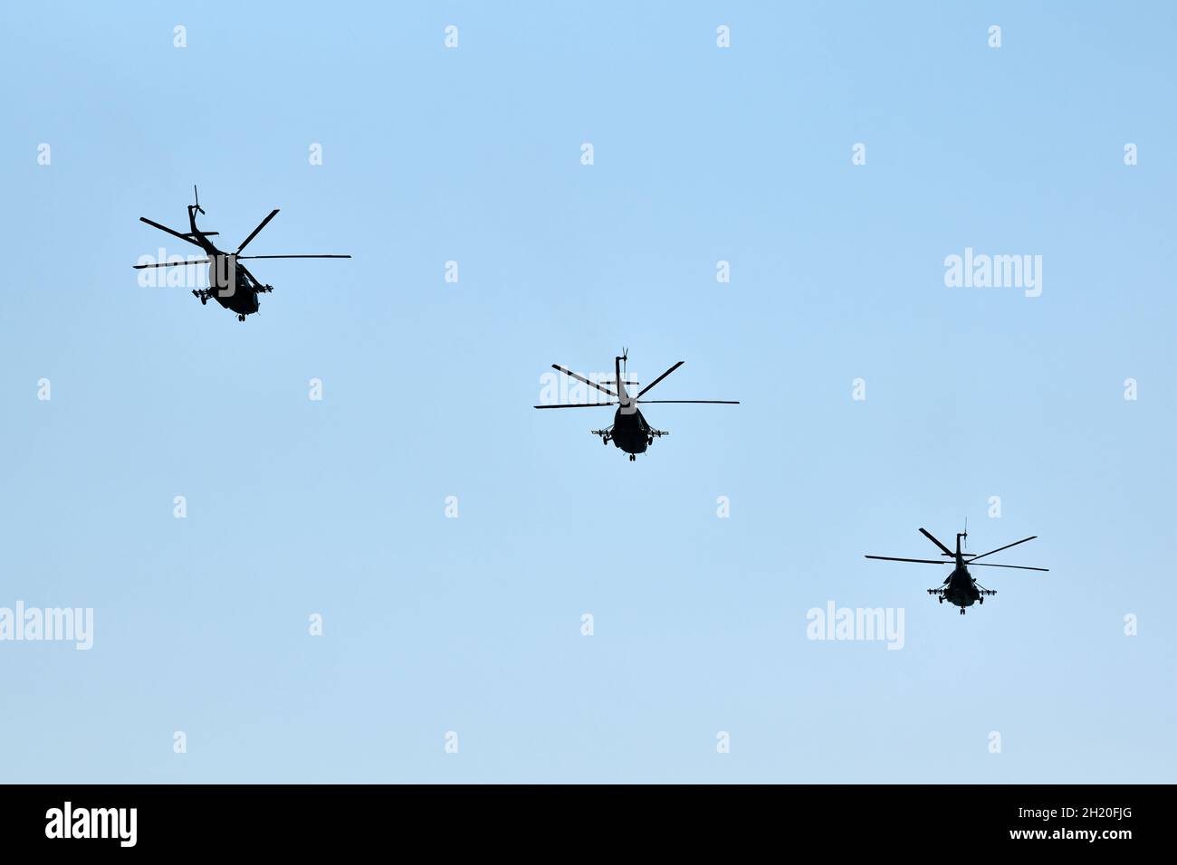 Military helicopters flying in bright blue sky performing demonstration ...