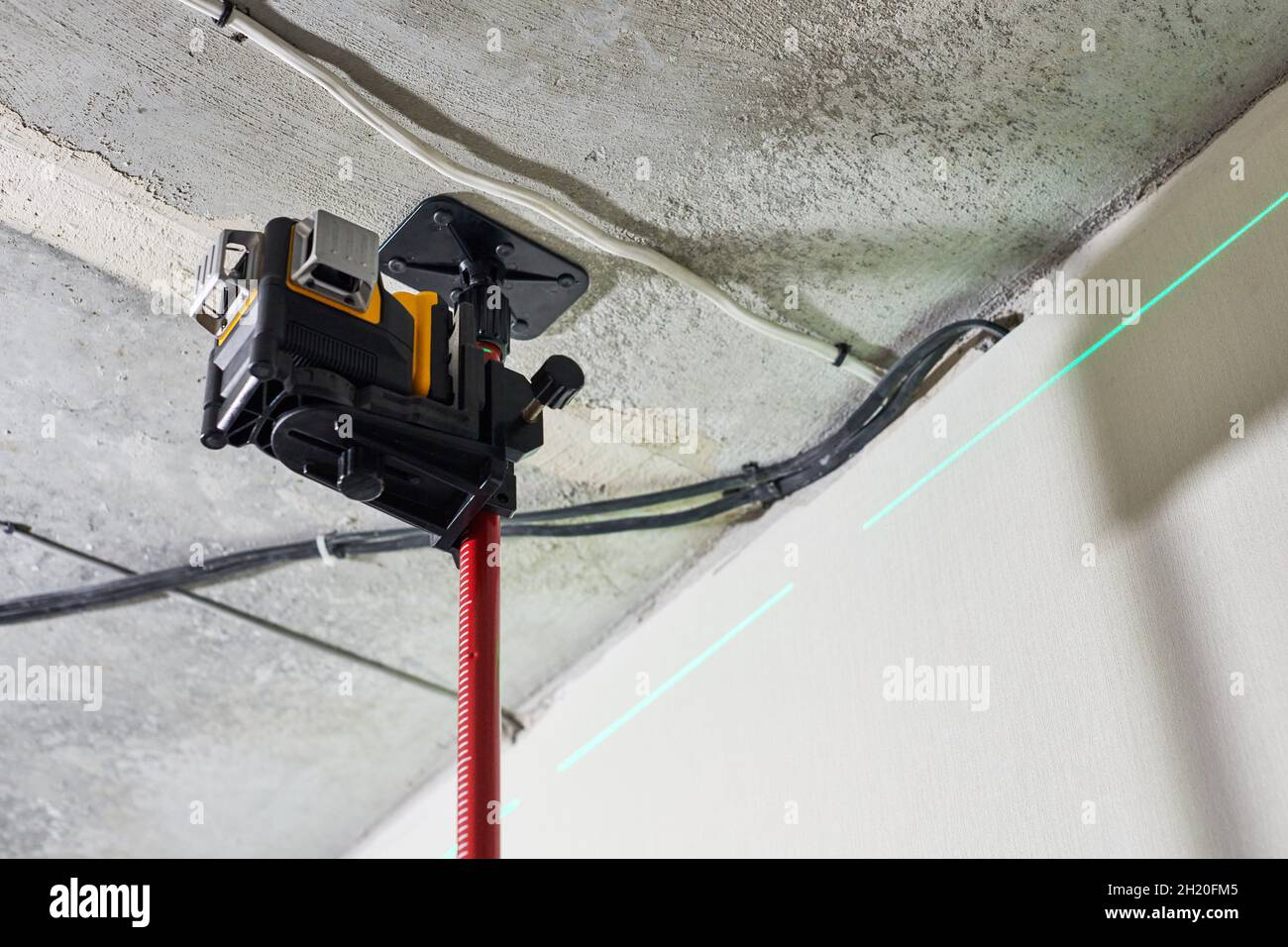 Laser level measuring tool with visible green laser beam on wall at ...