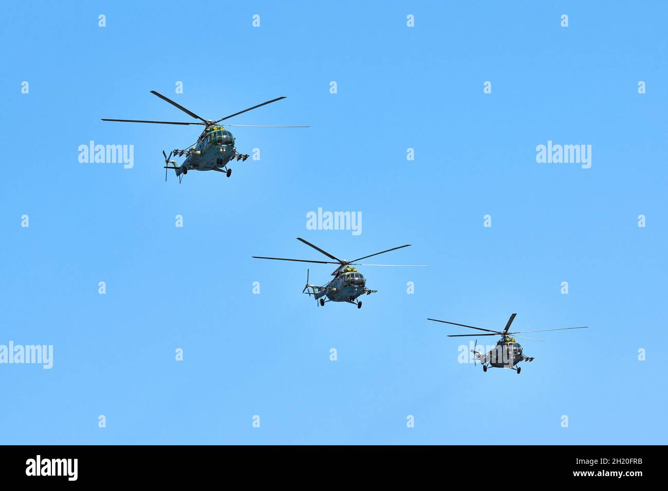 Three military helicopters flying in bright blue sky while performing ...
