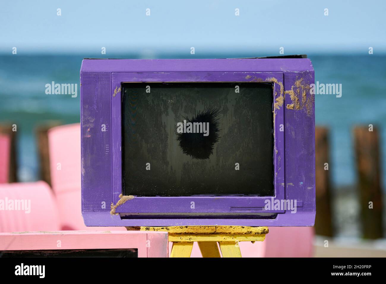 Old purple television with black broken screen on yellow vintage table ...