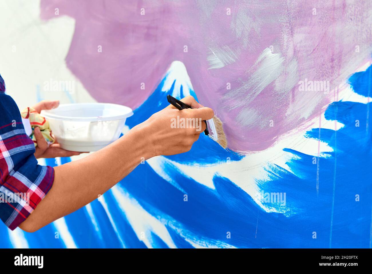 Female artist working on abstract acrylic painting, hand moving paint ...