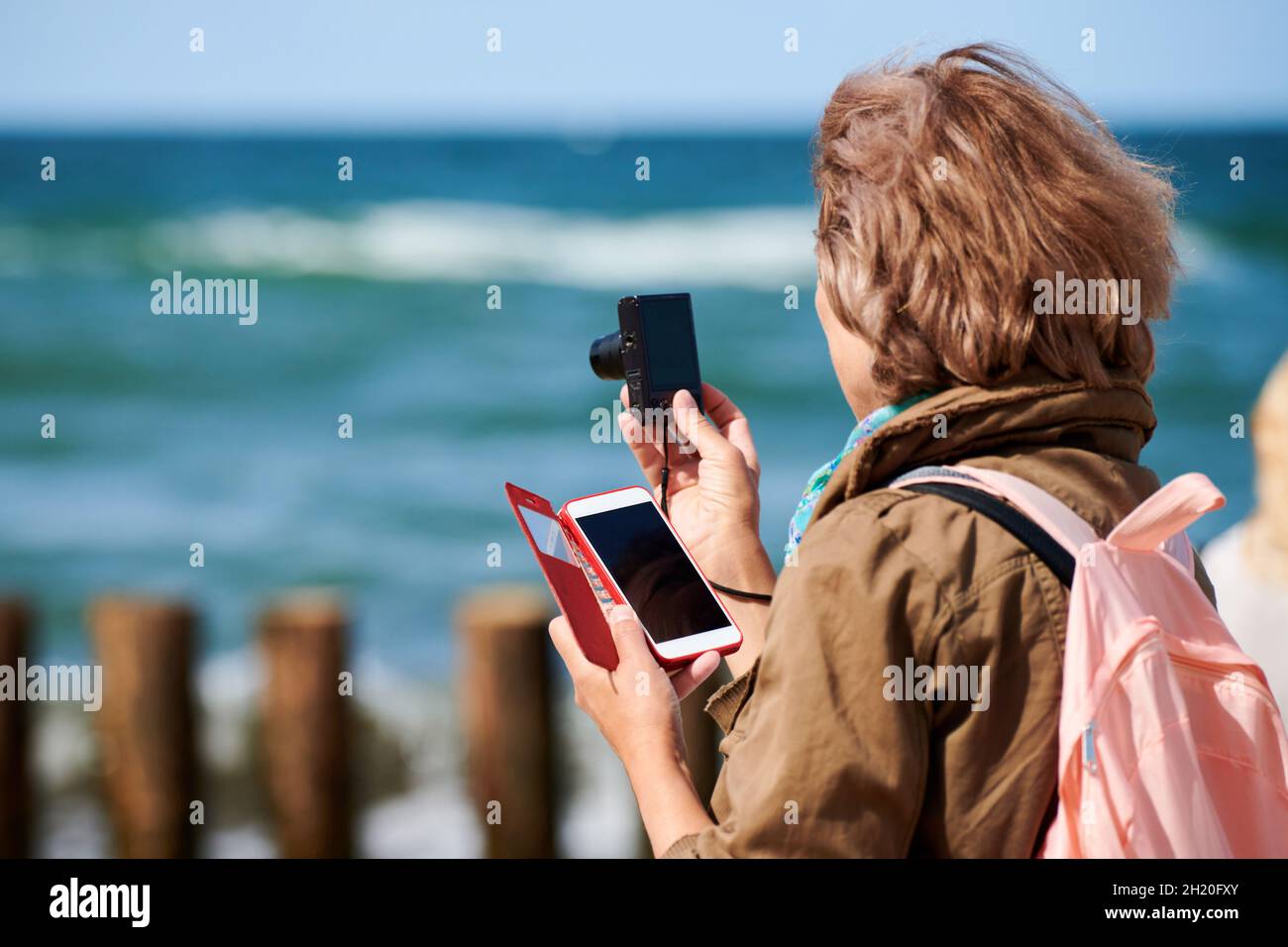 Brown-haired woman taking photos with digital camera, side view ...