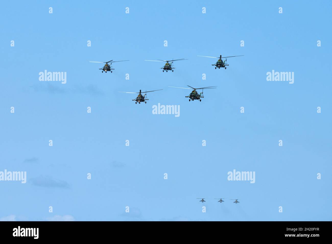 Military helicopters flying in bright blue sky performing demonstration ...