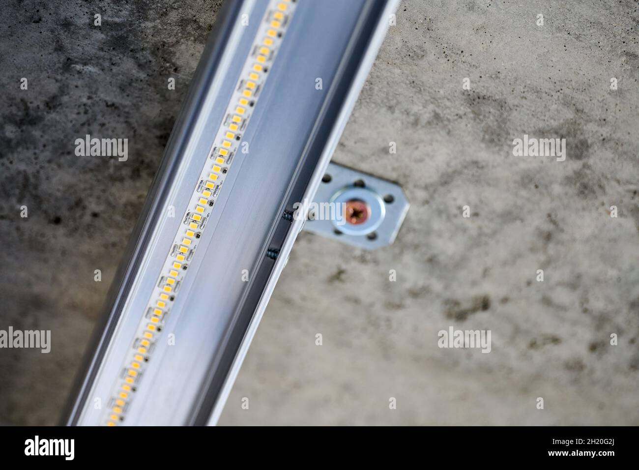 LED strip with aluminum profile on rough wall. Concrete ceiling with ...