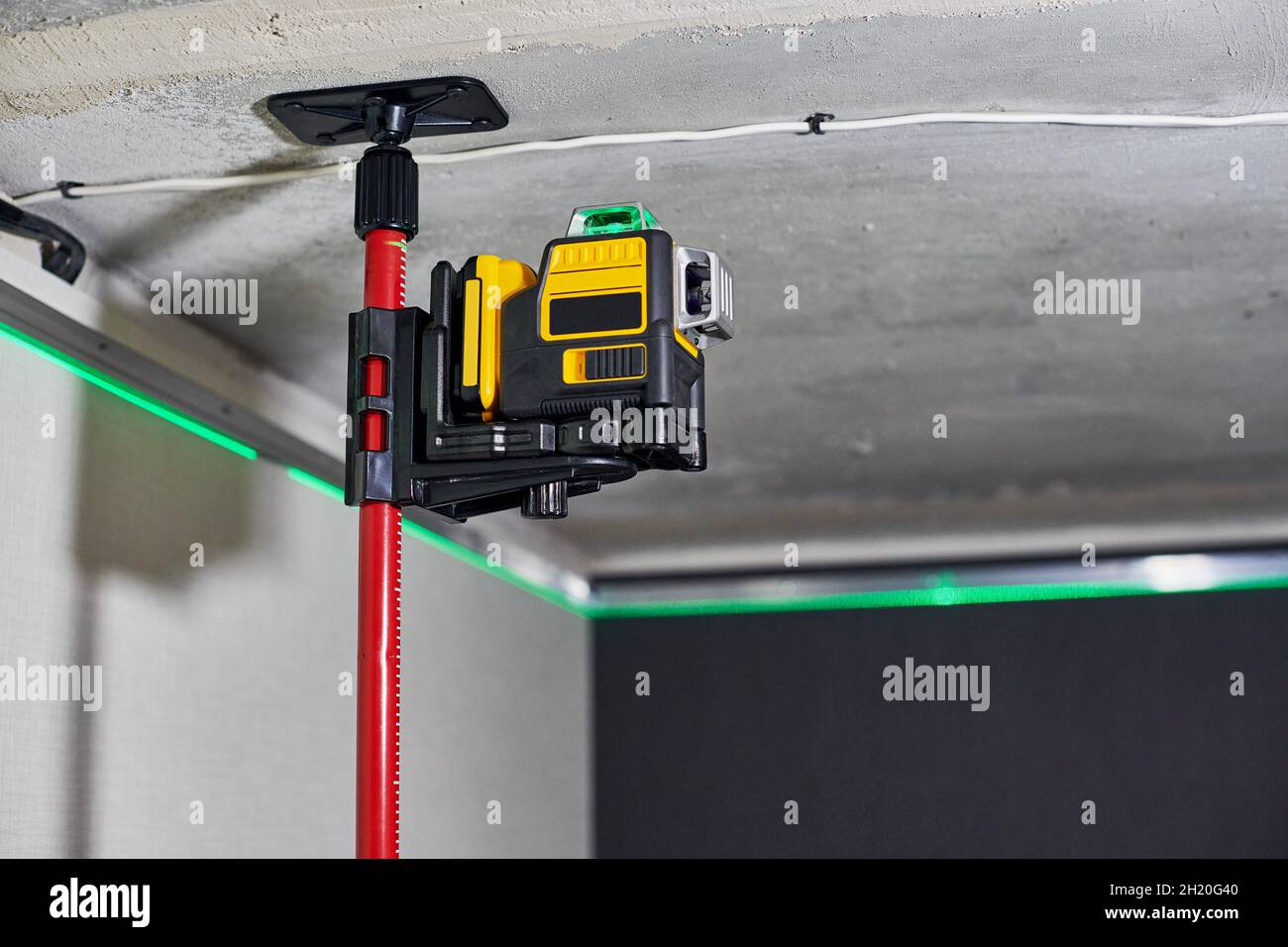 Laser level measuring tool with visible green laser beam on wall at ...